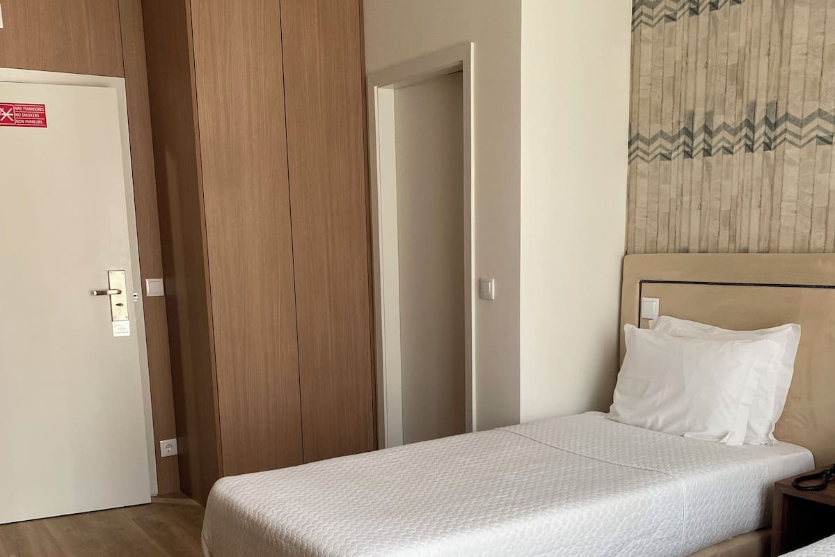 Quarto de hotel com cama, guarda-roupa, porta e parede com padrão.