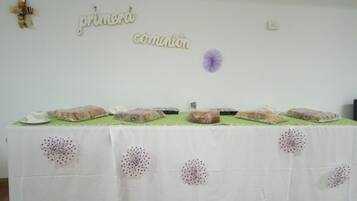 Mesa com toalha branca e decorações com bolinhas, coberta com embalagens de comida.