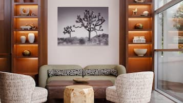 Uma sala de estar moderna com um sofá, duas poltronas, uma mesa de centro e uma estante com objetos decorativos.
