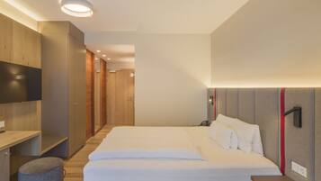 Quarto de hotel moderno com uma cama grande, uma escrivaninha e um guarda-roupa.