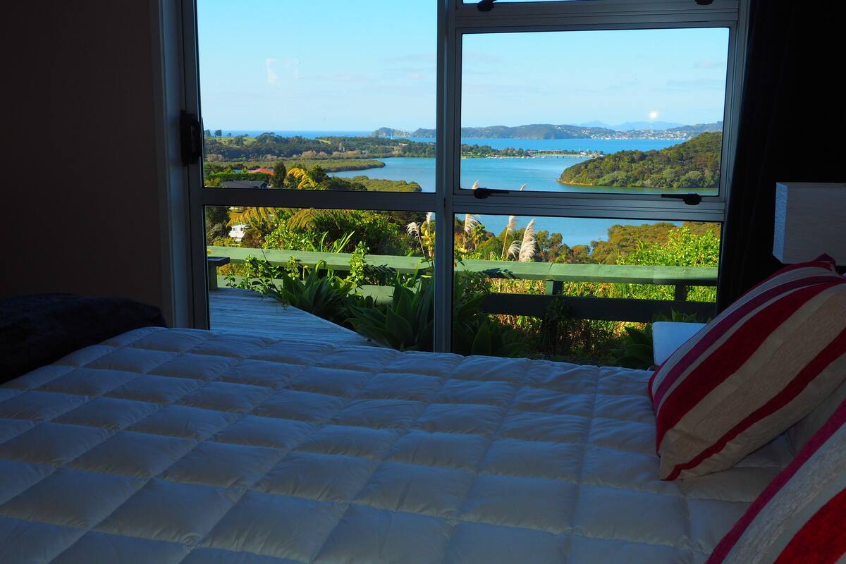Quarto com uma grande janela com vista para uma paisagem deslumbrante.