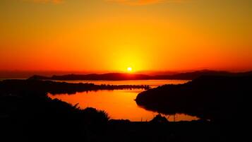 Pôr do sol sobre um lago, com o perfil de colinas ao fundo.