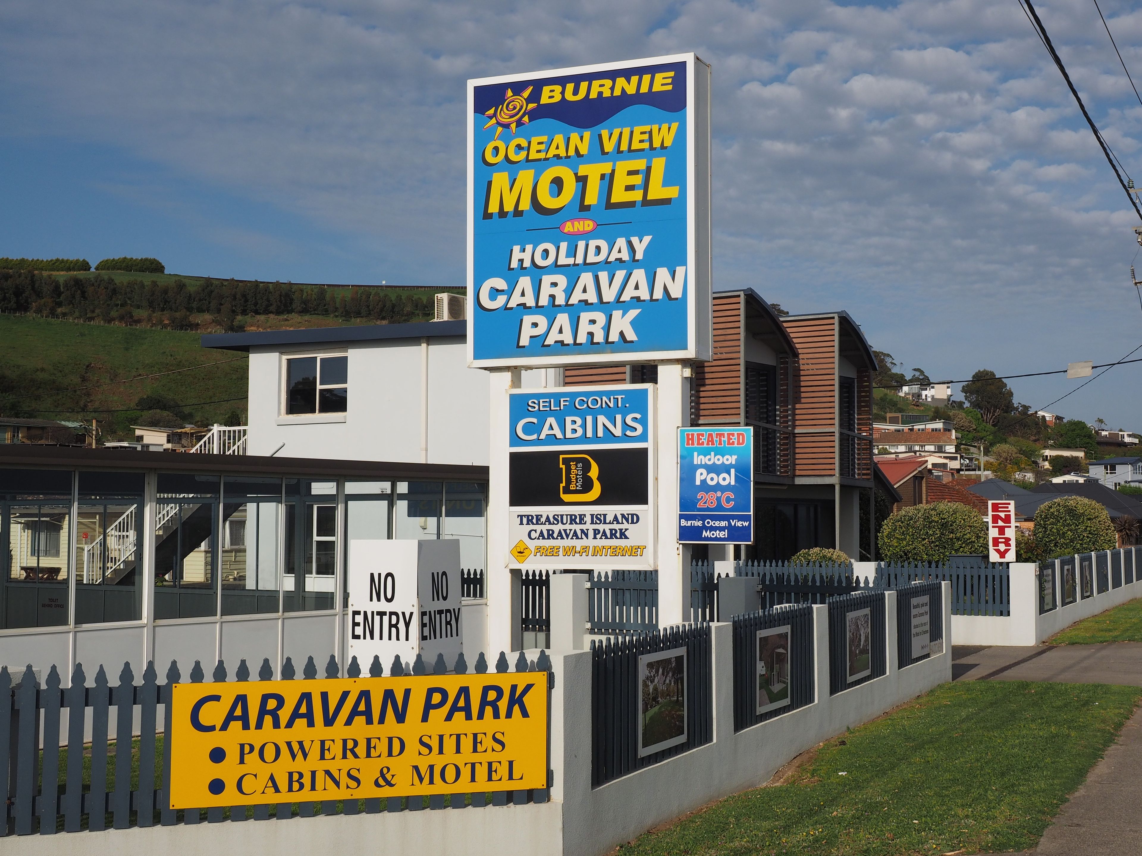 Placa do Burnie Ocean View Motel e Holiday Caravan Park, indicando comodidades como cabines independentes, piscina aquecida coberta e áreas com eletricidade.