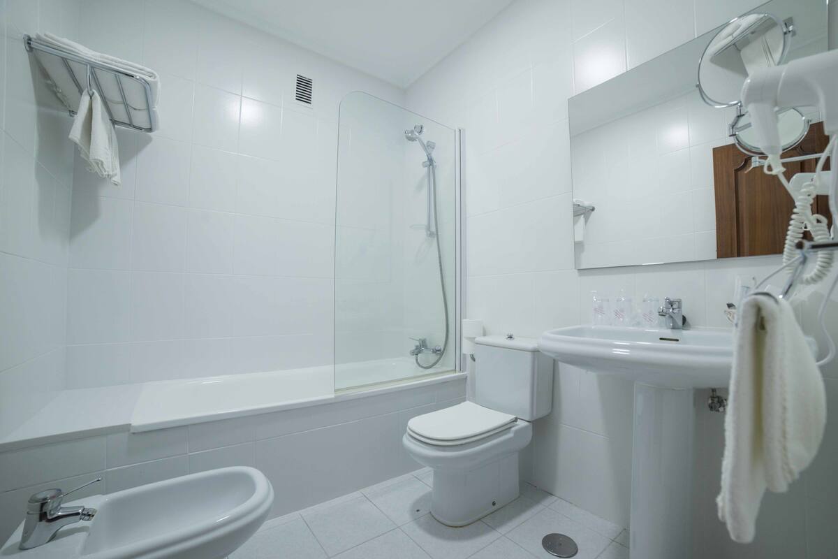 Uma casa de banho moderna com cabine de duche em vidro, lavatório branco e bidé.