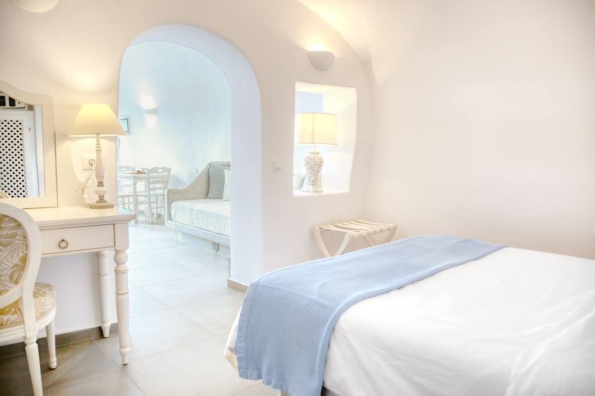 Quarto com cama, escrivaninha, cadeira e janela com luminária.