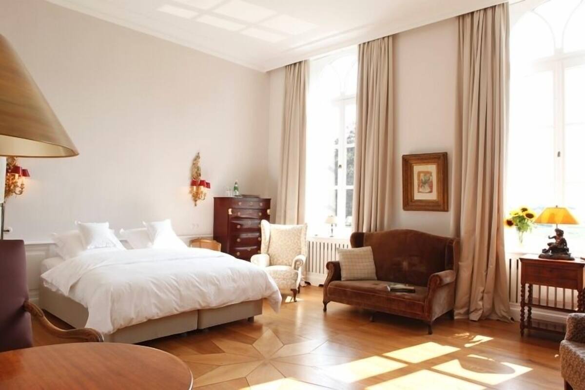 Quarto de hotel com cama, poltrona, sofá, cômoda e mesa.