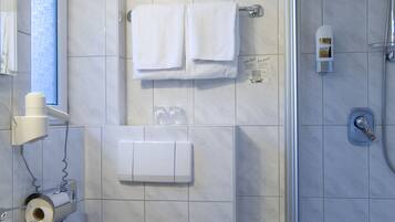 Uma casa de banho moderna com chuveiro, sanita, lavatório e suporte para toalhas.
