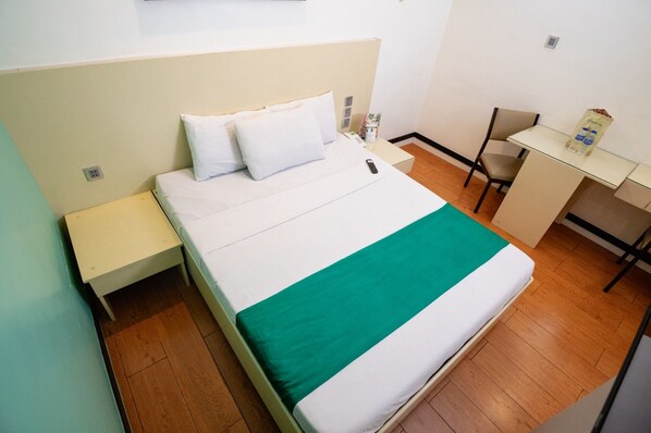 Quarto de hotel com uma cama, uma escrivaninha e uma cadeira.