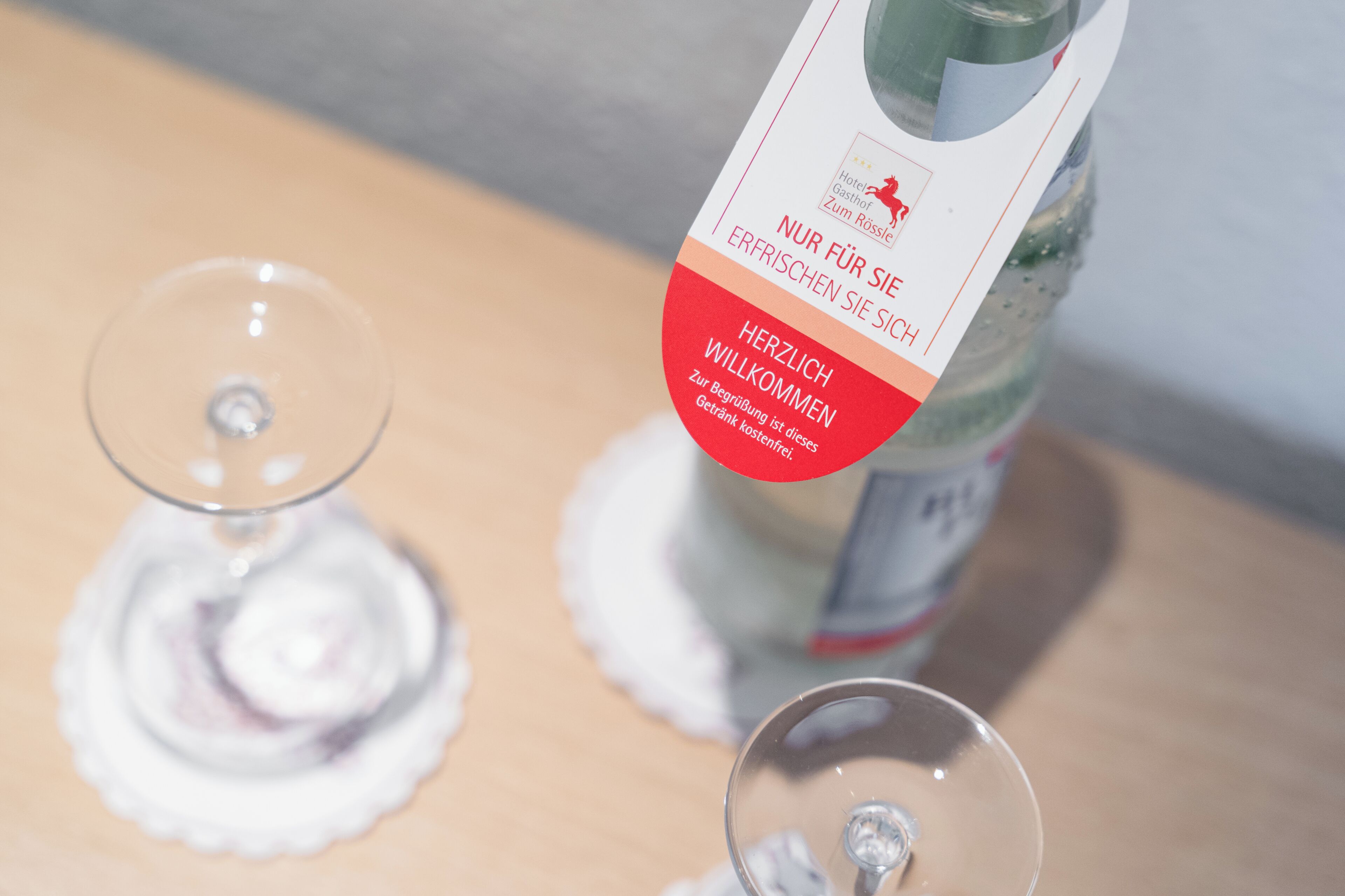 Uma garrafa de vinho com etiqueta e duas taças de vinho sobre uma superfície de madeira.