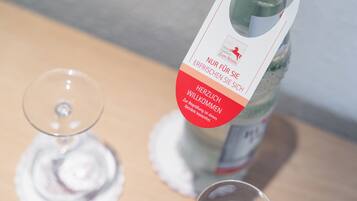 Uma garrafa de vinho com etiqueta e duas taças de vinho sobre uma superfície de madeira.
