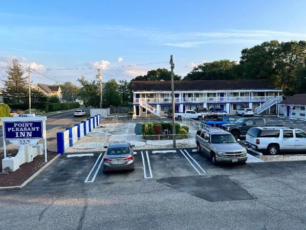 Um motel com placa, várias vagas de estacionamento e um edifício com varanda.