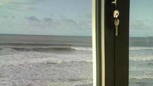 Vista do oceano através de uma janela, com uma porta visível à direita.