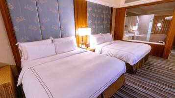 Quarto de hotel com duas camas, um espelho grande e uma cabeceira de madeira.