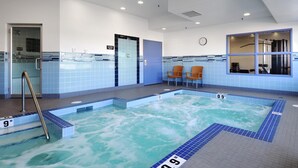 Piscina interior com profundidade de 9 metros, vestiários próximos e um relógio visível na parede.