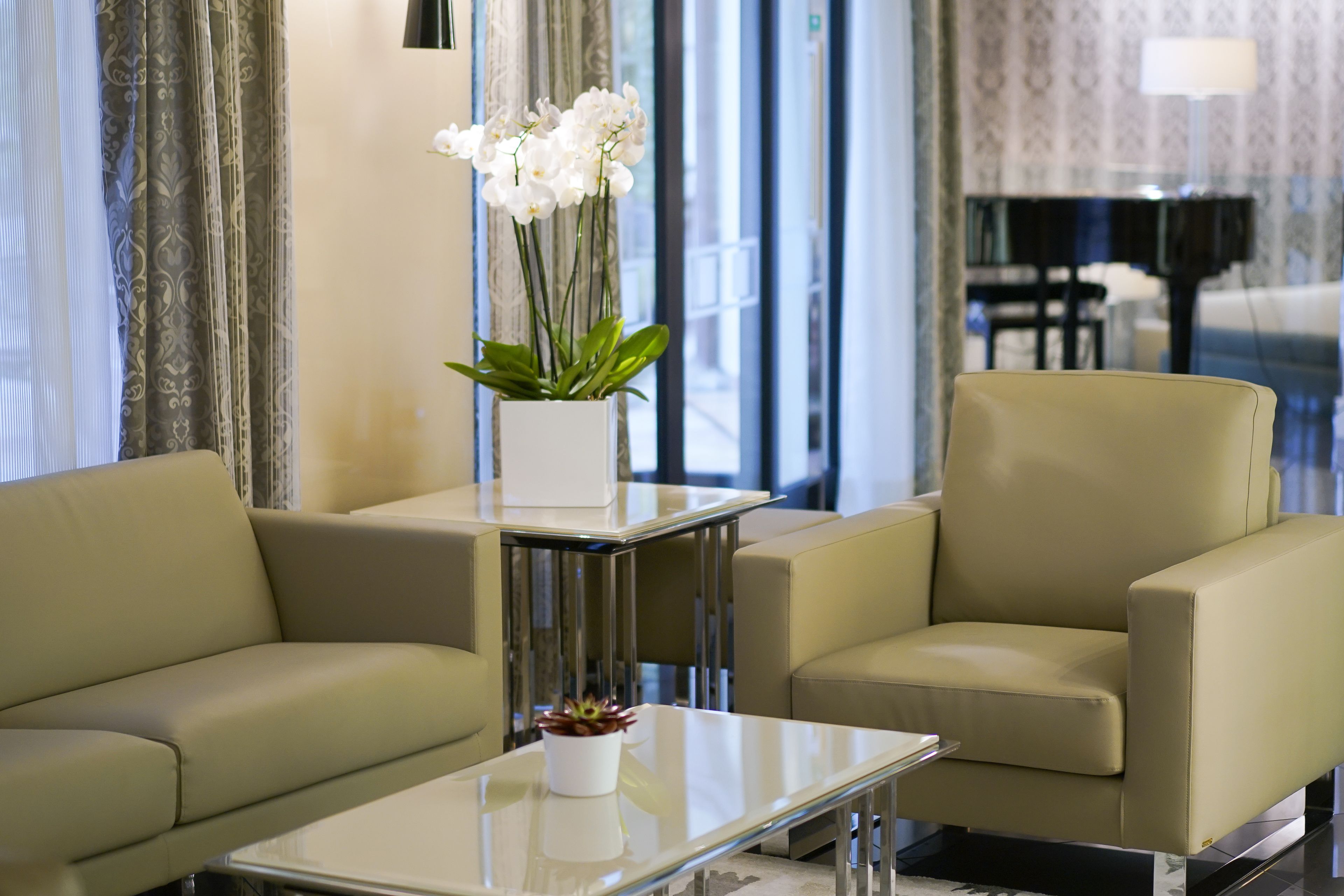 Um lobby moderno com sofá, poltrona e mesa de centro de vidro com planta em vaso.