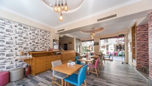 Um restaurante com mesas e cadeiras de madeira, uma área de cozinha e uma parede estampada.