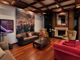 Uma sala de estar com lareira, um quadro grande e uma televisão exibindo 'Bienestar & Relax'.