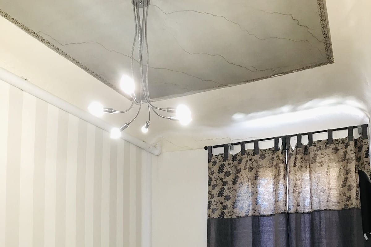 Quarto de hotel com cama, uma cadeira e área de chuveiro.