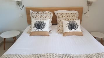 Quarto de hotel com uma cama, duas mesas de cabeceira e luminárias fixadas na parede.