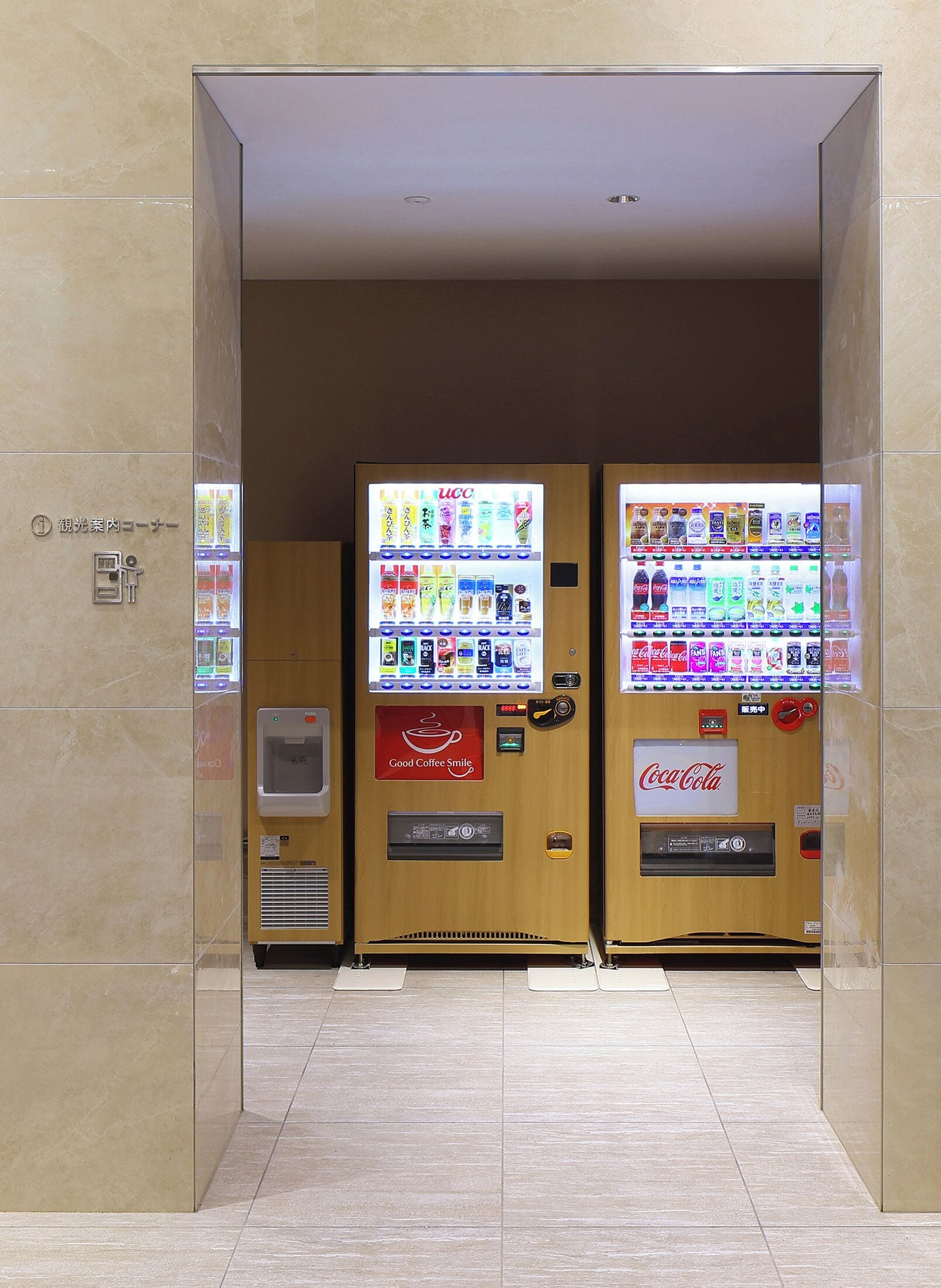 Espaço com máquinas de venda automática, incluindo uma máquina de Coca-Cola e outra com um letreiro vermelho que diz 'Bom Café Sorriso'.