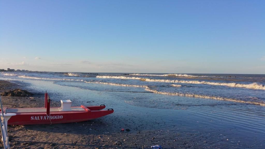Um barco vermelho chamado 'SALVATAGGIO' numa praia com ondas.