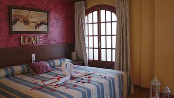 Quarto de hotel com uma cama, um quadro na parede e uma janela com cortinas.