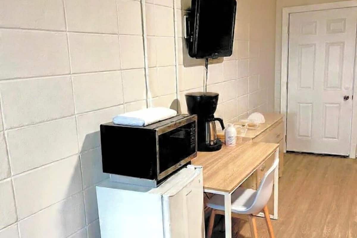 Cozinha compacta com micro-ondas, cafeteira e pequena geladeira.