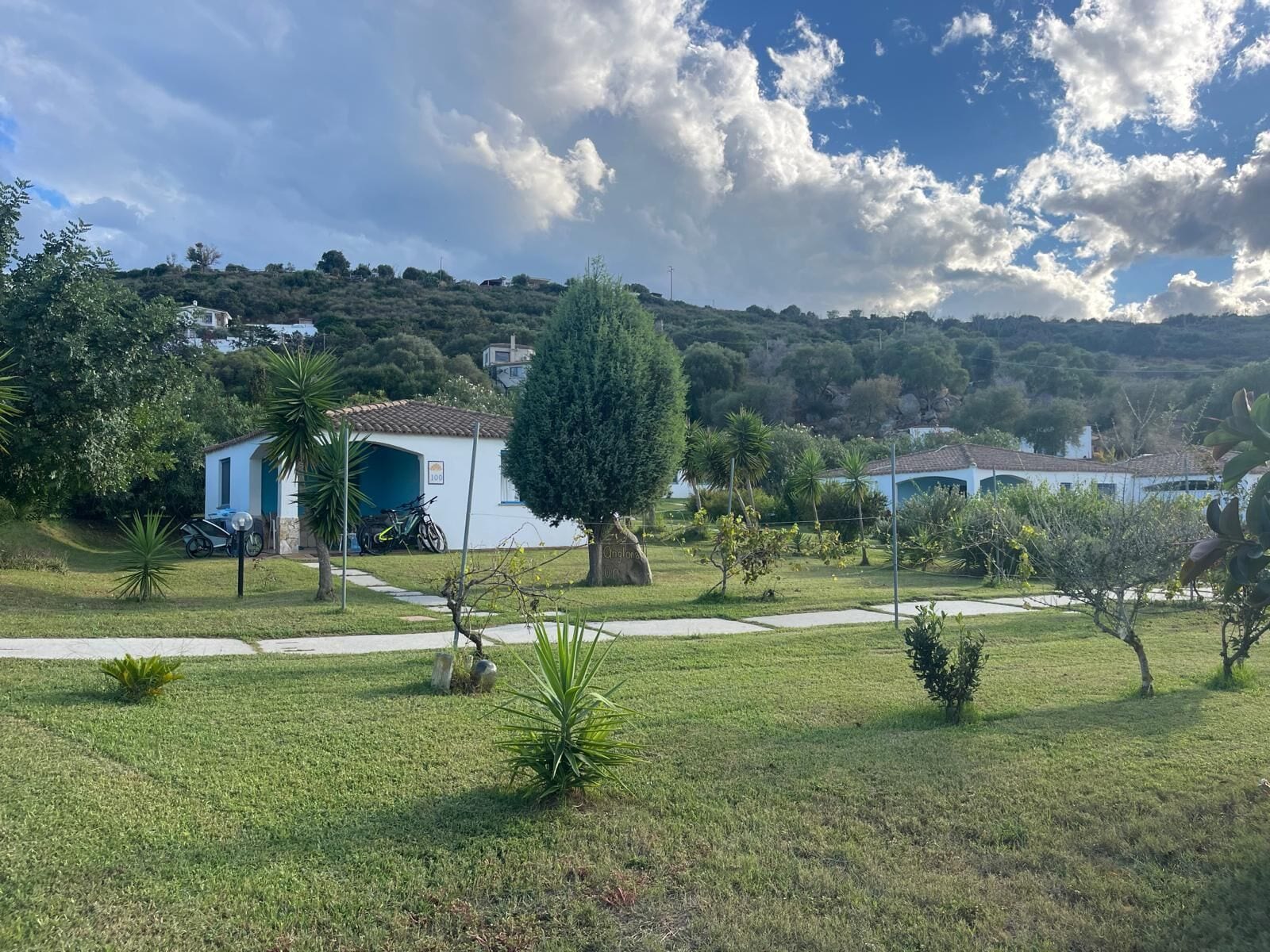 Área residencial com casas, um caminho pavimentado e uma colina ao fundo.