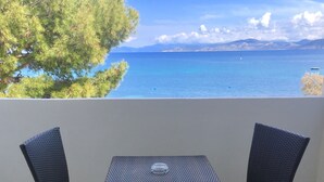 Varanda com uma mesa e duas cadeiras, com vista para um corpo de água e montanhas ao longe.