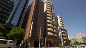 Um edifício com vários andares, com espaços comerciais e residenciais, com diversos letreiros e um céu claro.