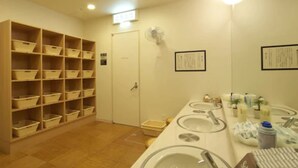 Casa de banho com várias pias, espelho e prateleiras de arrumação.