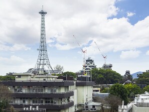 Um edifício moderno com vários andares, uma torre imponente e arquitetura japonesa tradicional ao fundo.