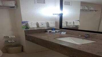 Uma casa de banho com lavatório, espelho, porta-toalhas e artigos de higiene pessoal.