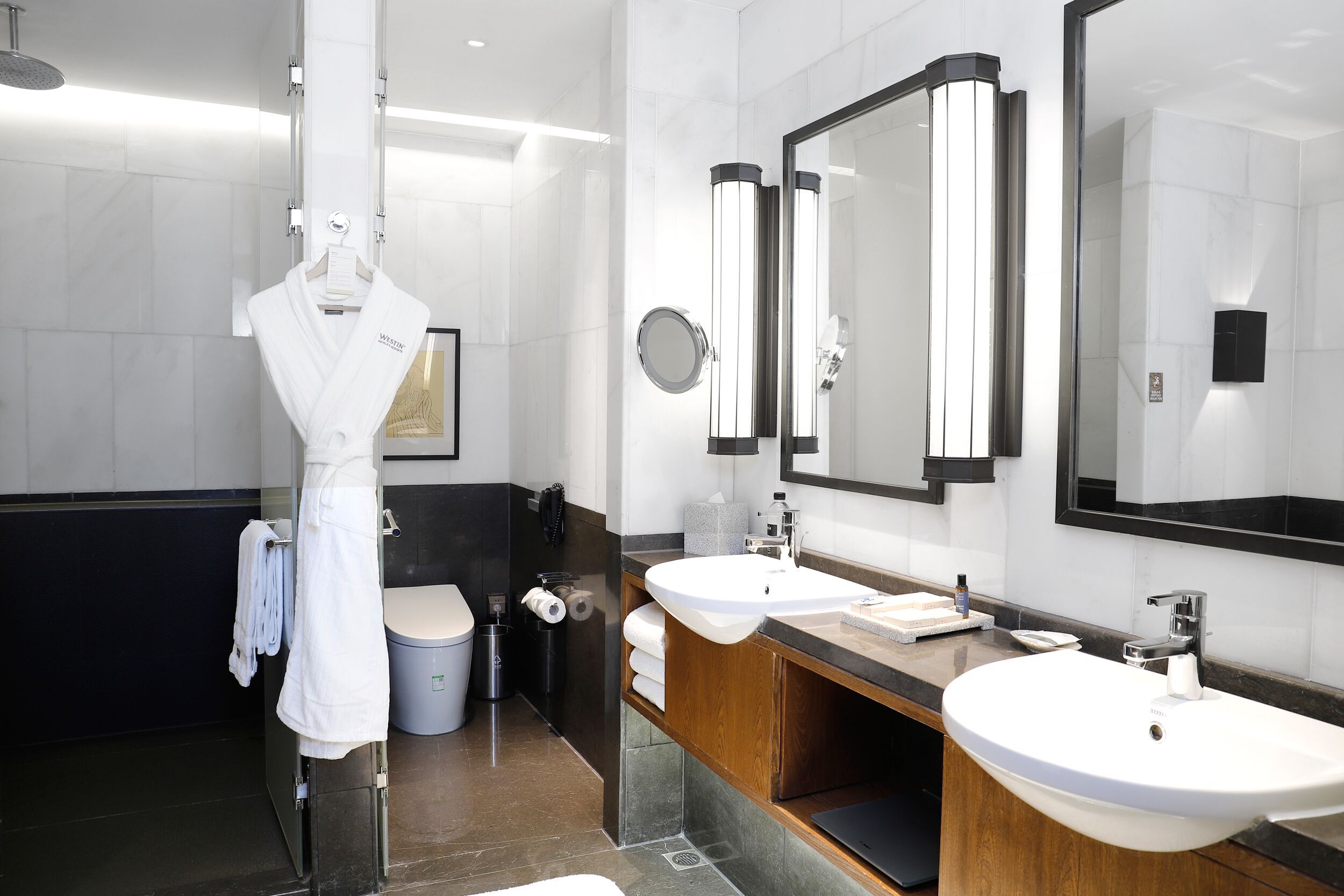 Um banheiro moderno com duas pias, um espelho grande e um porta-robes.
