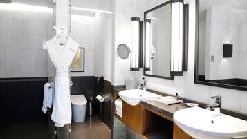 Um banheiro moderno com duas pias, um espelho grande e um porta-robes.