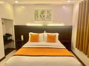 Quarto de hotel com uma cama, mesa de cabeceira, luminária e obra de arte na parede.