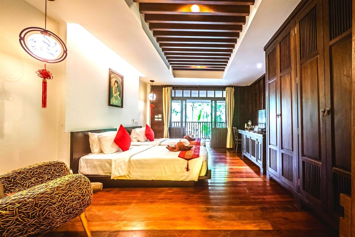 Quarto de hotel com cama, uma cadeira, uma escrivaninha e vista para o exterior.