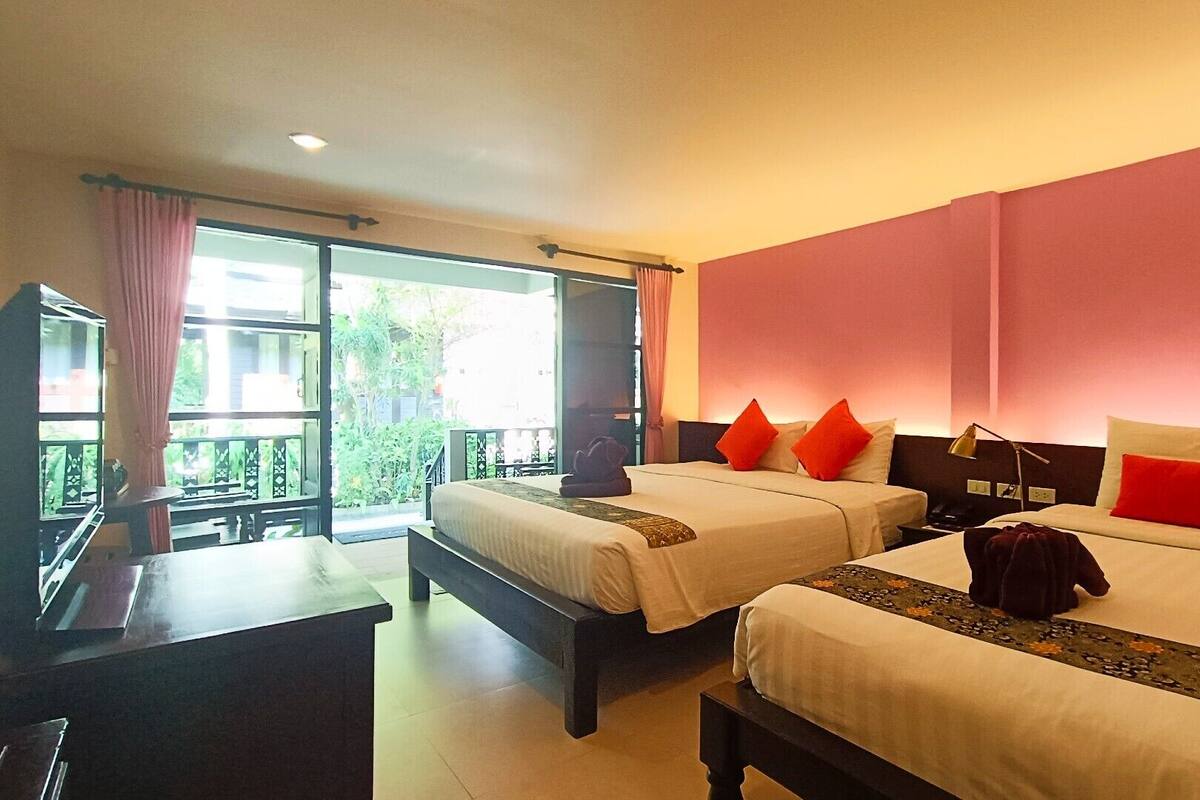 Quarto de hotel com duas camas, uma mesa de trabalho e varanda com vista para o verde.