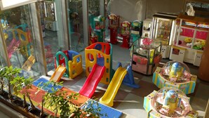 Espaço infantil com escorregadores, estruturas de escalada e jogos de fliperama.