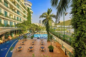 Um hotel com piscina no terraço, área de estar externa e vegetação exuberante.