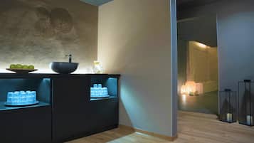 Interior moderno com console escuro exibindo uma tigela de maçãs, um jarro e copos.