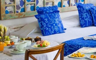 Uma área de refeições com uma mesa posta para o café da manhã, incluindo pratos de comida, xícaras e um vaso de flores.
