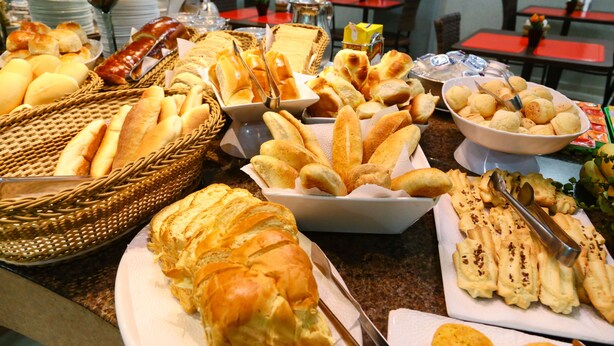Um buffet com diversos pães e doces.