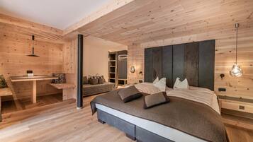 Quarto moderno com teto de madeira, uma cama grande com várias almofadas, mesa de cabeceira e um espaço para escritório.
