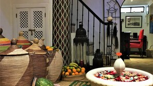 Uma sala de estar com cestos de vime, uma fruteira e uma fonte decorativa.