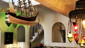 Uma escadaria imponente com parede estampada em padrão de zebra, um modelo de navio pendurado e lustres elaborados.