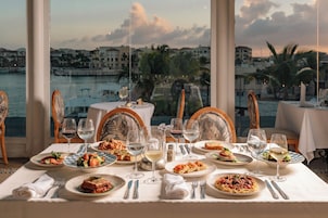 Mesa posta para jantar, com vista para um porto e edifícios.