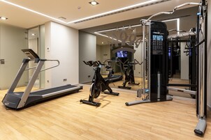 Academia moderna com esteiras, bicicletas ergométricas e máquinas de musculação.