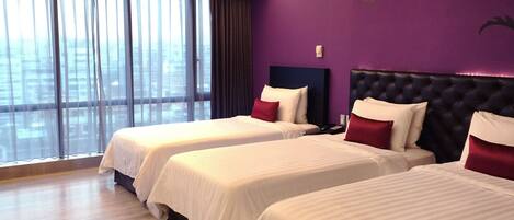 Quarto de hotel com duas camas, um lustre, vista para a cidade e paredes roxas.