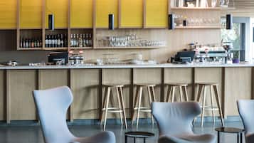 Uma área de bar moderna com balcão, banquetas e prateleiras com copos e garrafas.